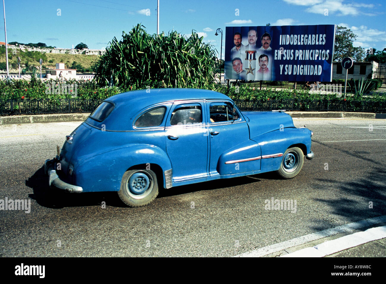 Blue Cuban car driving down Havana road with billboard dipicting the ...