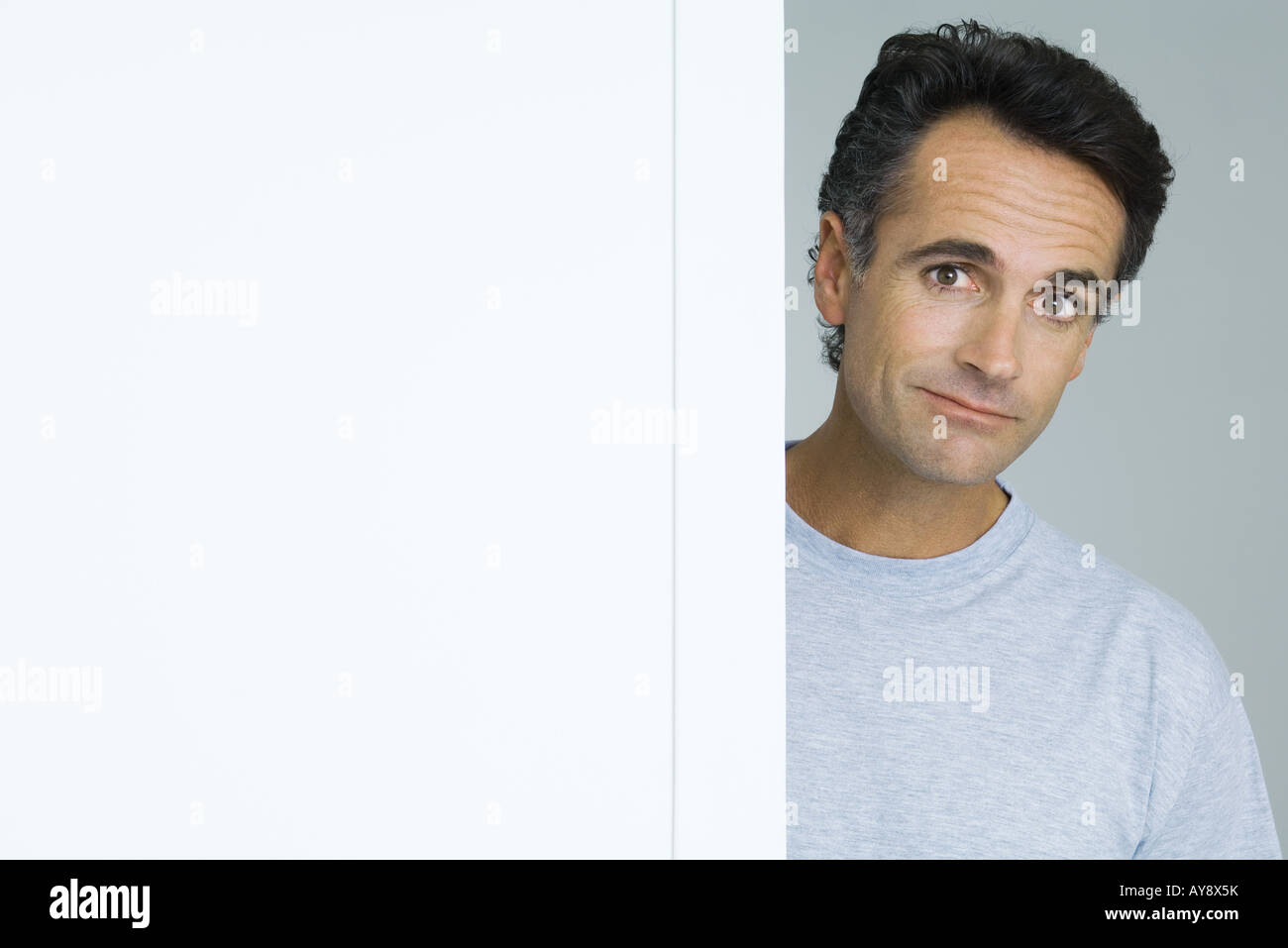 Man looking around corner of wall, portrait Stock Photo - Alamy