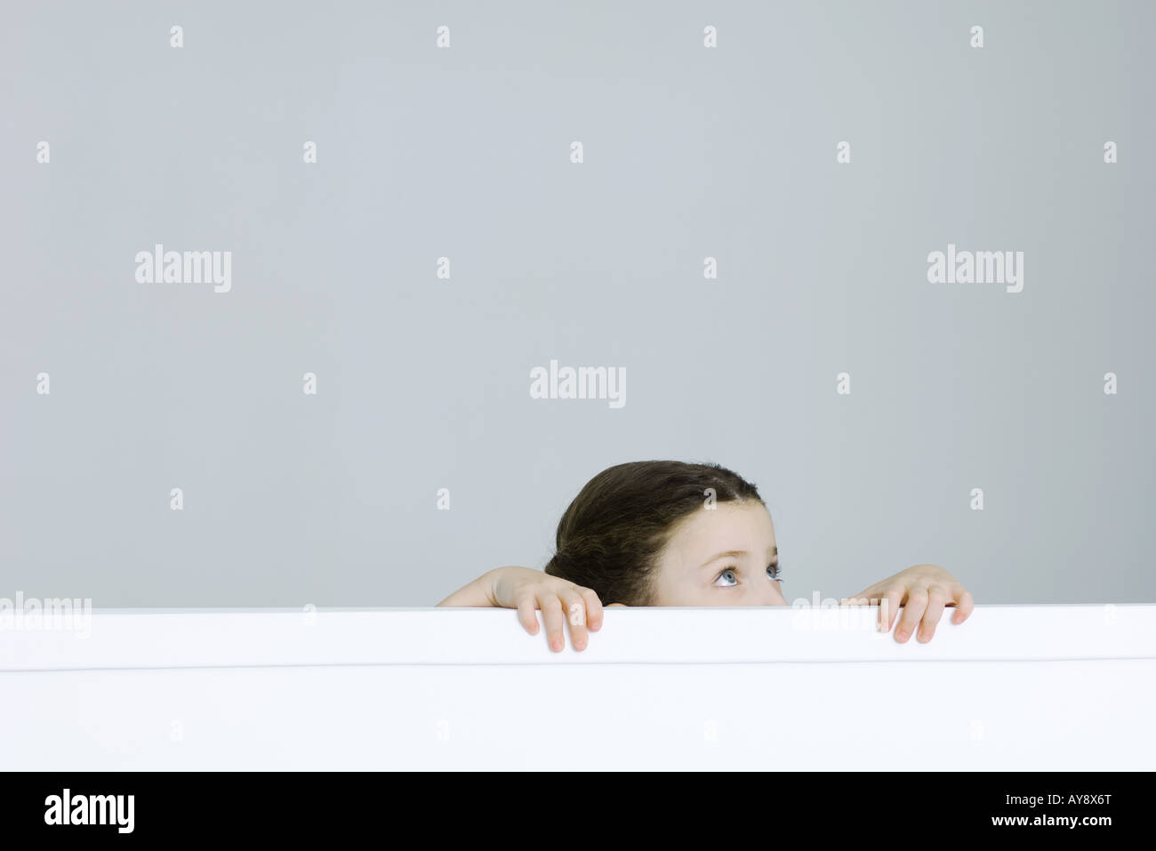 Little girl peeking over ledge Stock Photo - Alamy