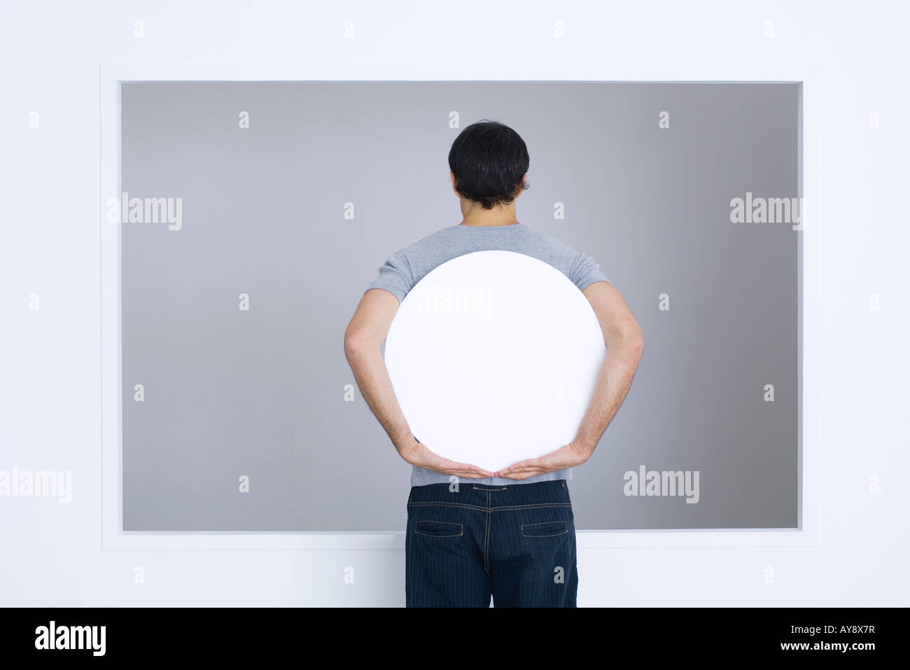 Man holding round sign behind back, rear view Stock Photo - Alamy