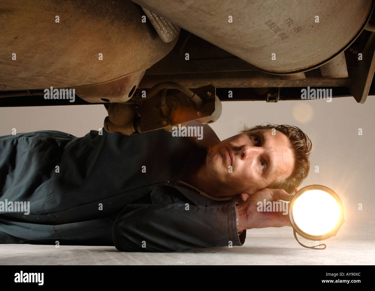 Mechanic inspecting under a car Stock Photo - Alamy