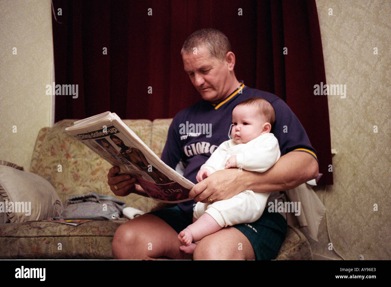 Father caring for baby while trying reading newspaper Stock Photo - Alamy
