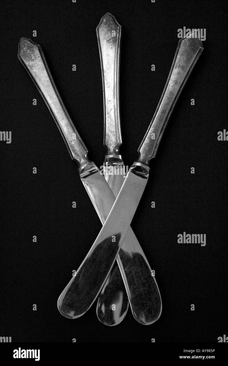 A monochrome image of three silver knives with blades crossing Stock ...