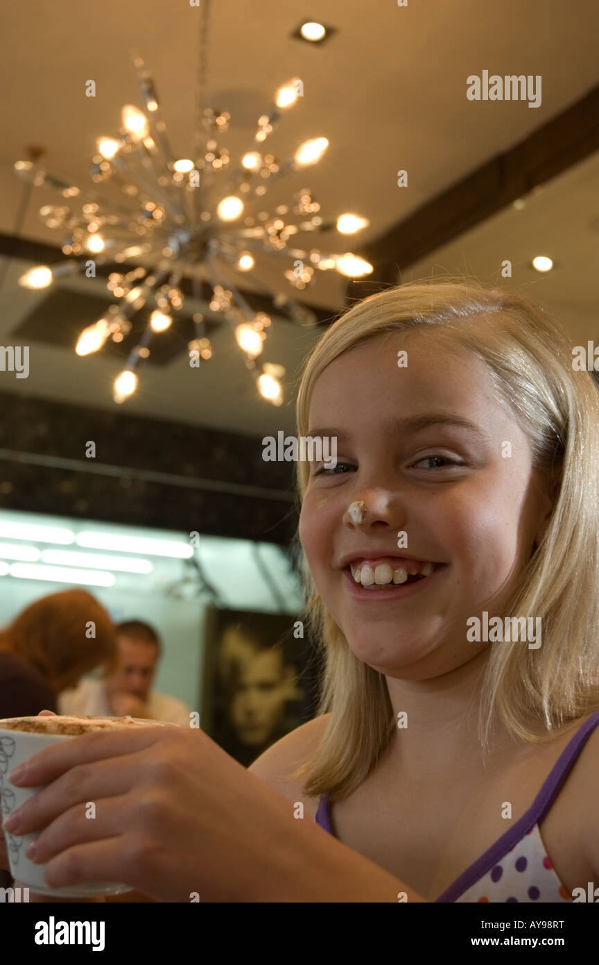 Girl in Cafe drinking hot chocolate with cream on nose Stock Photo - Alamy