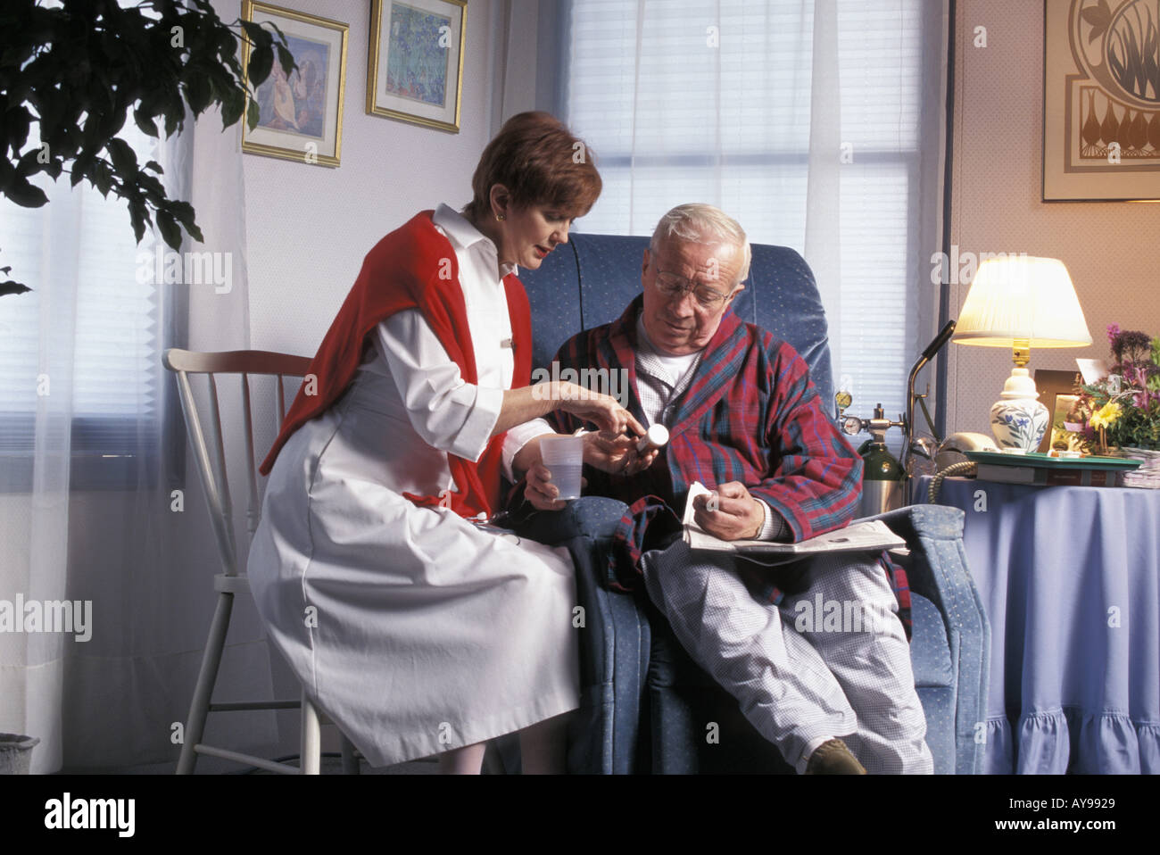 Visiting nurse reviewing medication with homebound senior male patient ...