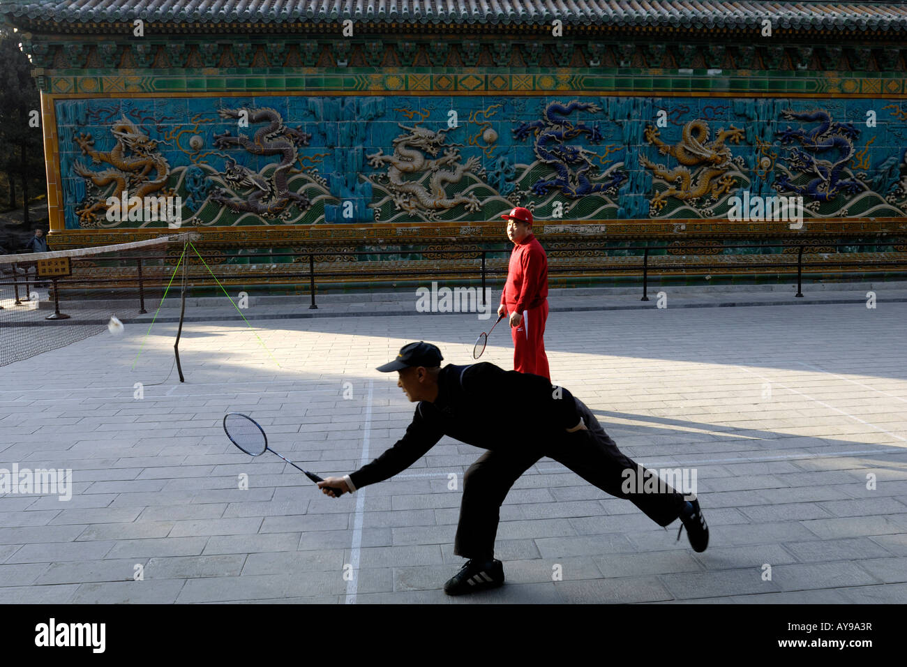 Two men play badminton in the morning in front of Nine Dragons Wall at ...