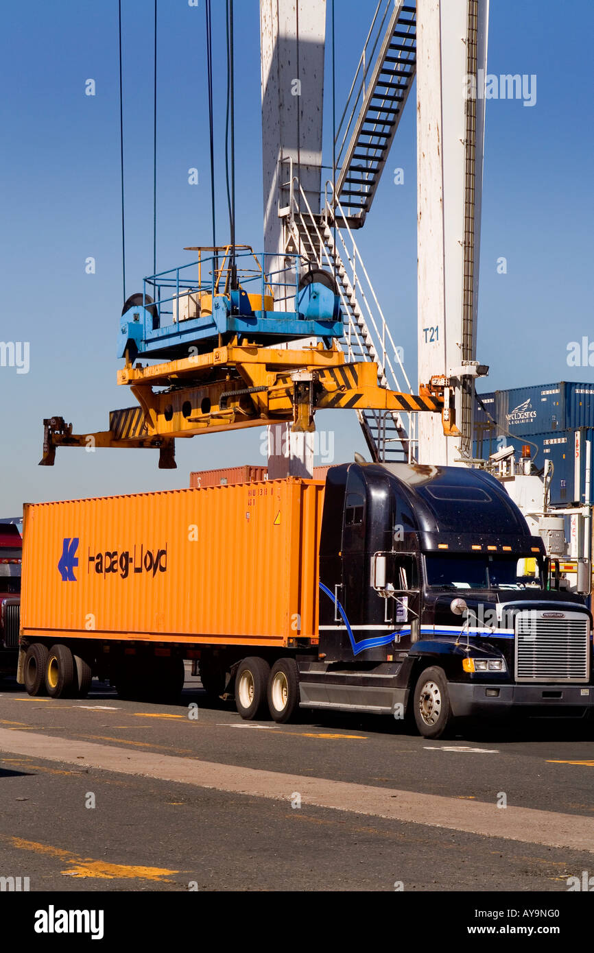 An overhead crane prepares to latch onto a maritime cargo container ...