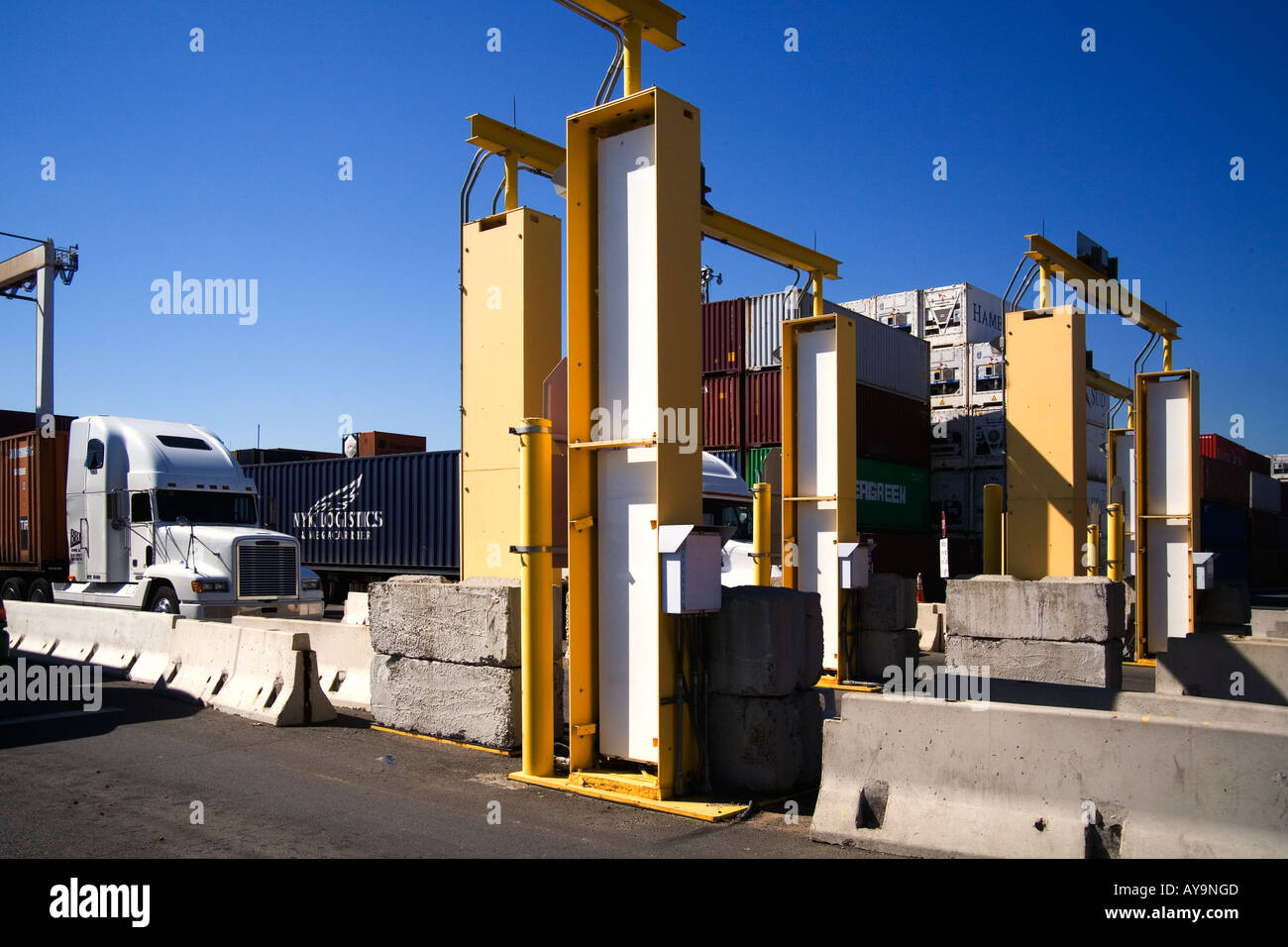 Trucks carrying maritime cargo containers prepare to pass between ...