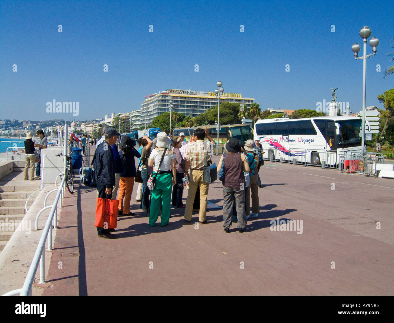 A freshly-disgorged busload of tourists on the Promenade des Anglais in ...