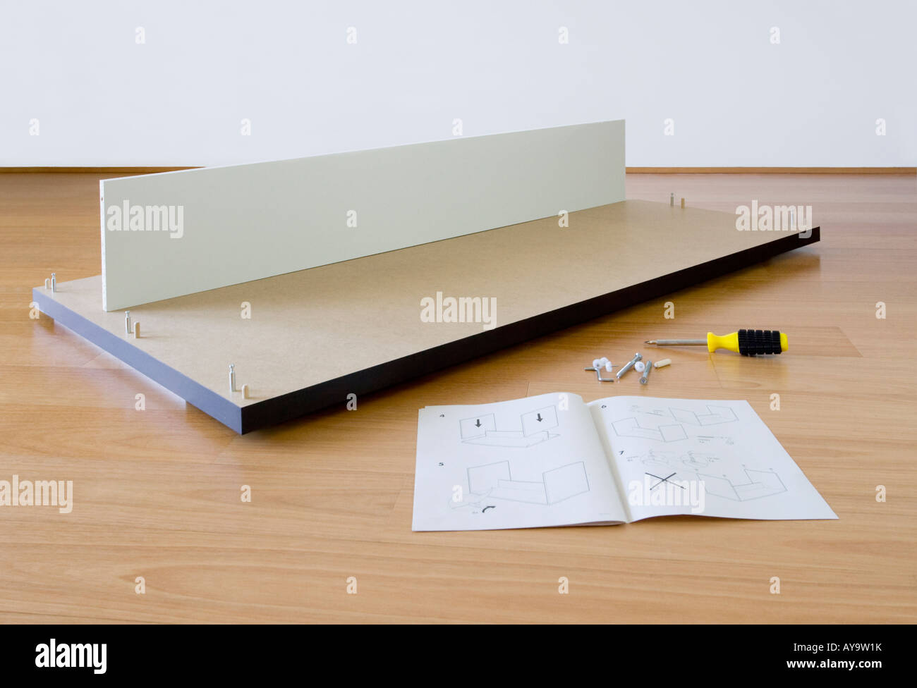The underside of a self-assembly desk with instructions, screws and a ...