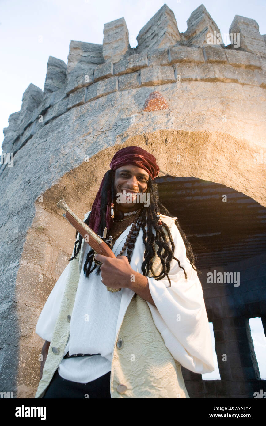 Portrait of a pirate armed with a gun standing outside a castle turret ...