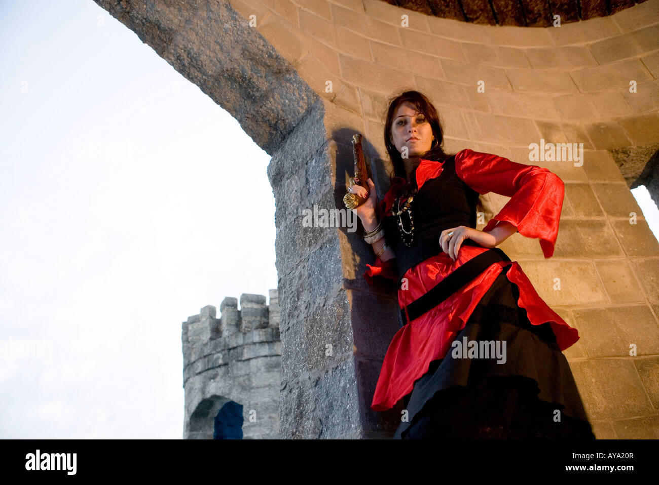 Portrait of a woman pirate armed with a pistol standing inside a castle ...