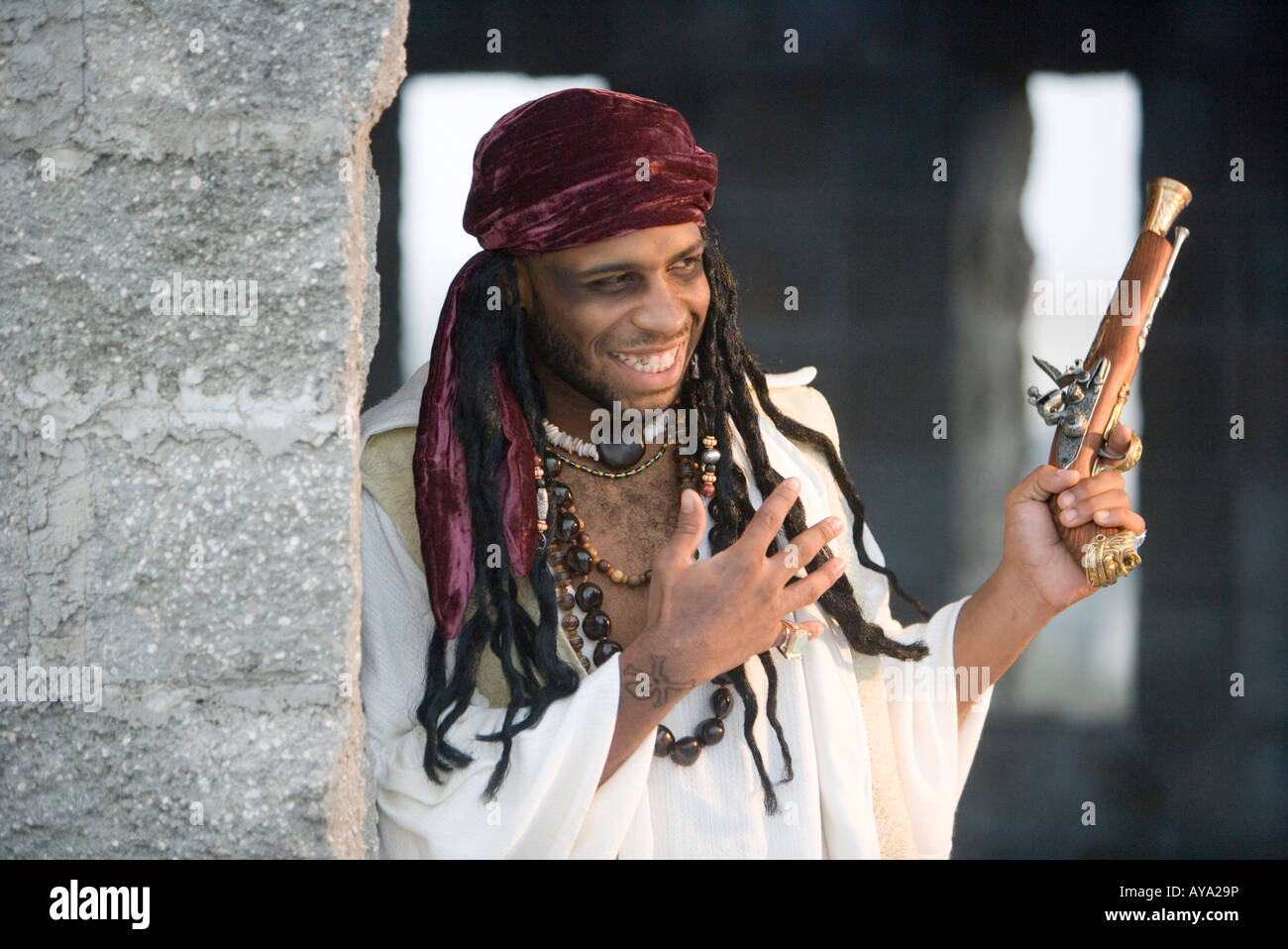 View of a smiling pirate armed with a pistol leaning against a castle ...