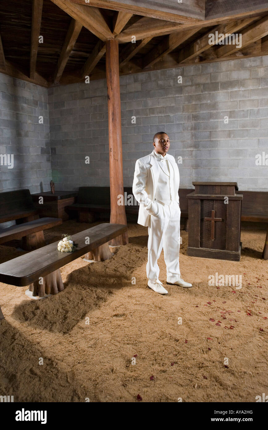 Portrait of a groom standing next to bouquet of roses resting on bench ...