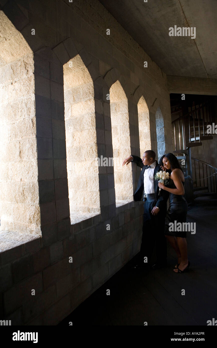 Young couple in formal attire looking out window of medieval castle ...