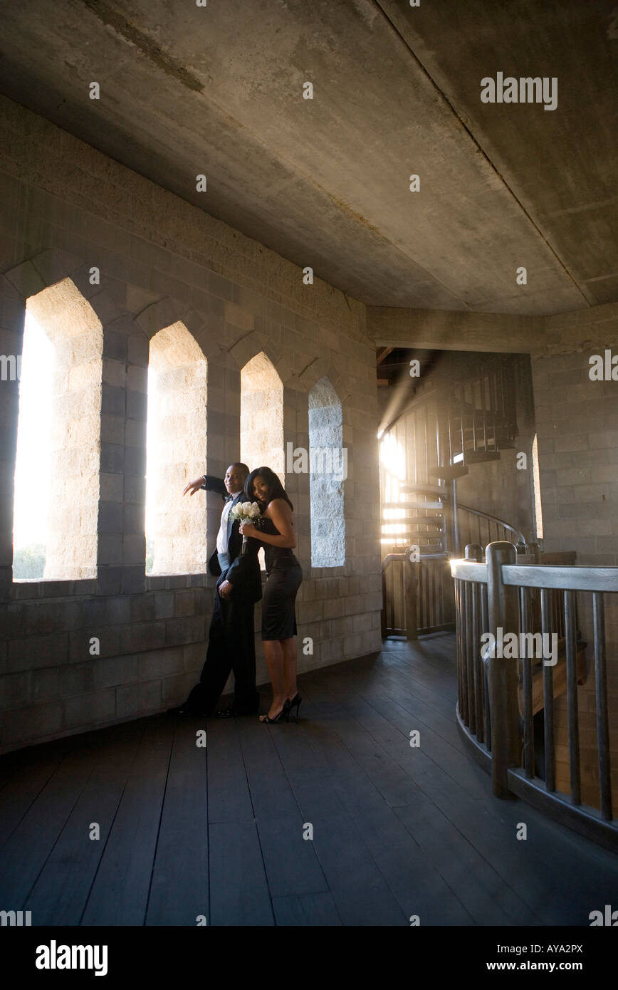Young couple in formal attire looking out window of medieval castle ...