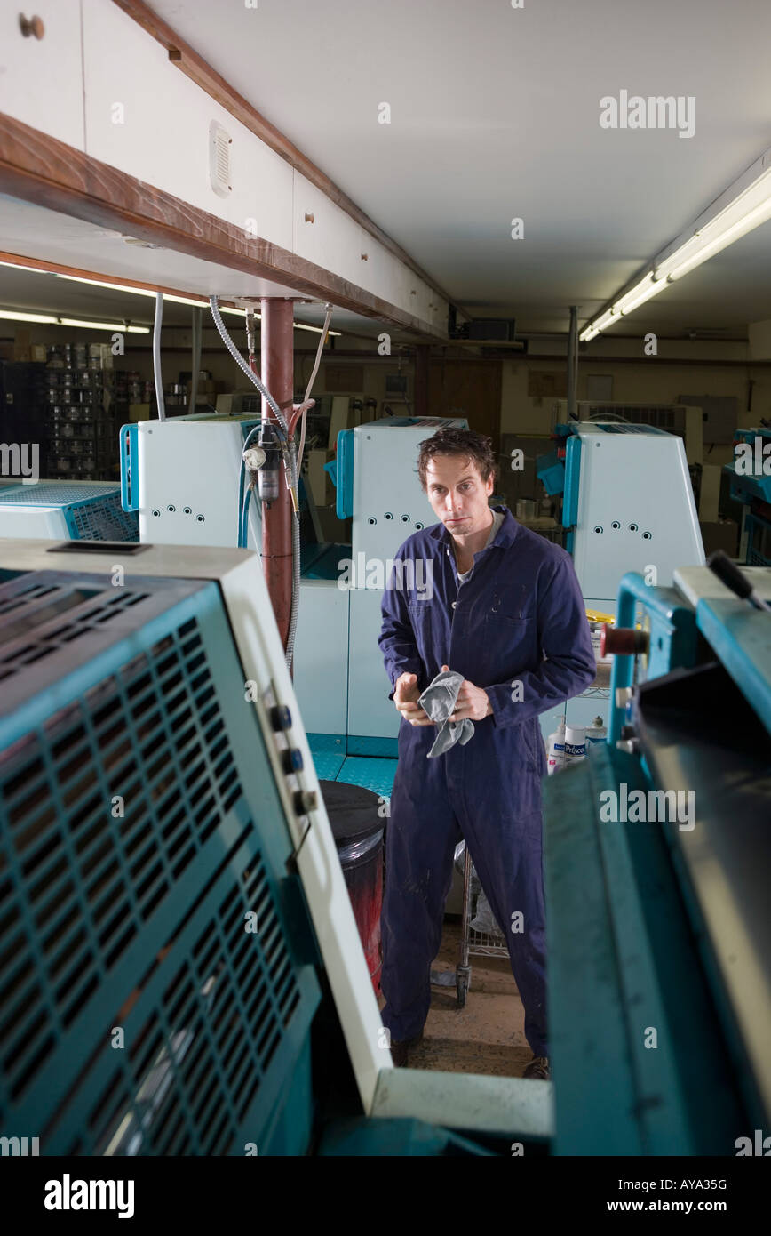 Portrait of a man in coveralls behind a printing machine Stock Photo ...