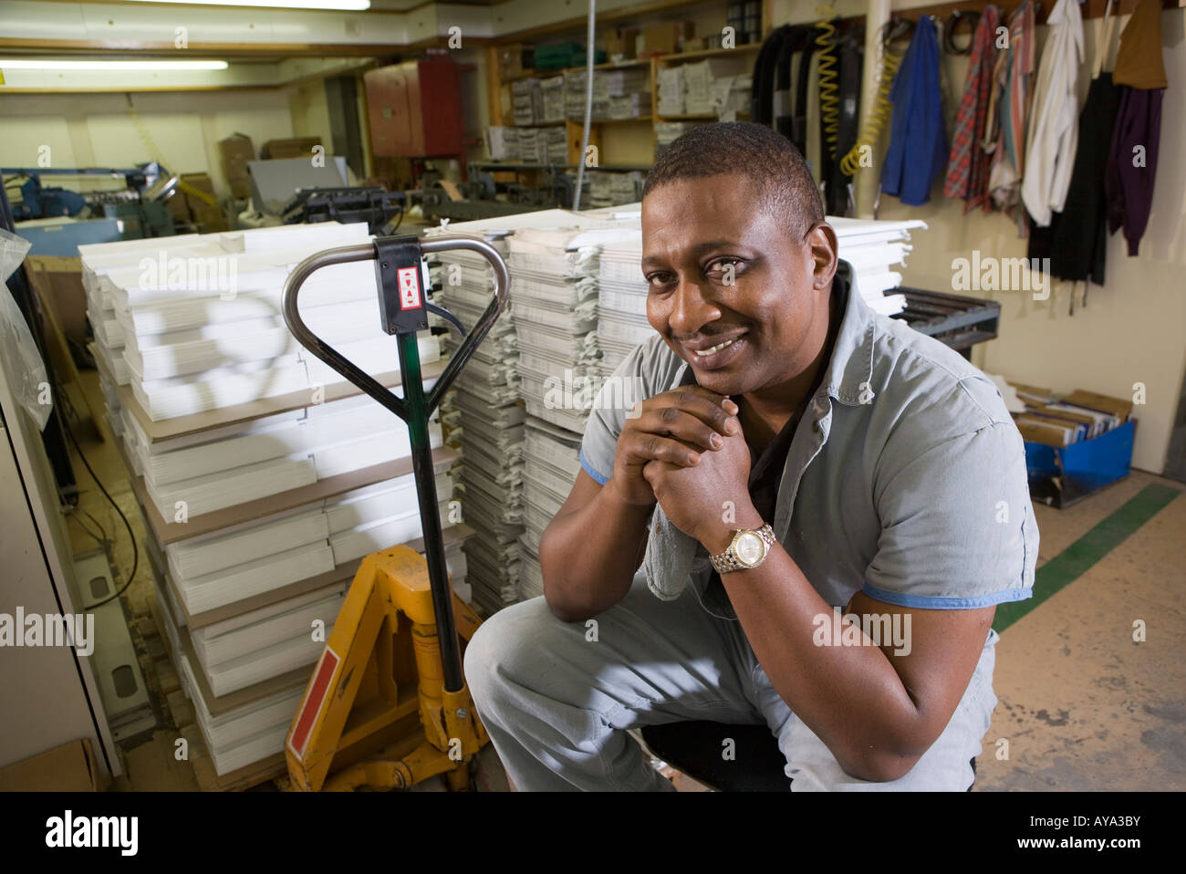 Portrait of a man sitting on a stool in a warehouse Stock Photo - Alamy