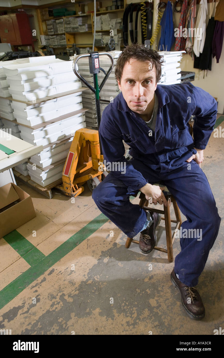 Portrait of a man sitting on a stool in a warehouse Stock Photo - Alamy