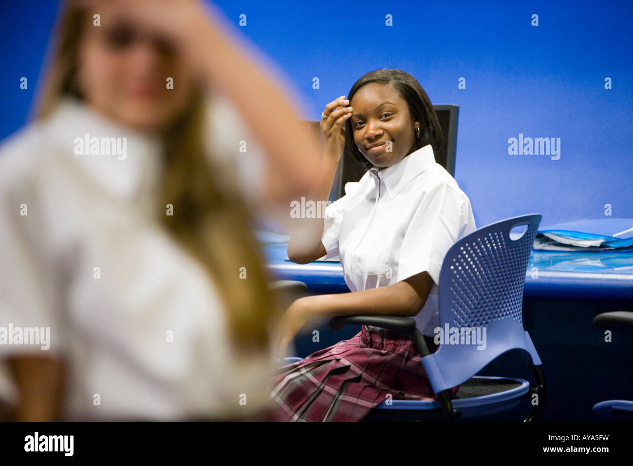 Portrait of a teenage girl student in uniform sitting in the computer ...