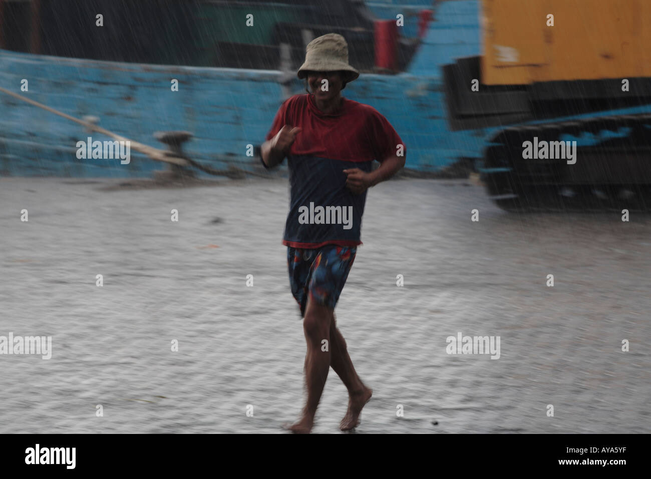 Indonesia Jakarta Young man running through rain storm at Old Harbor at ...