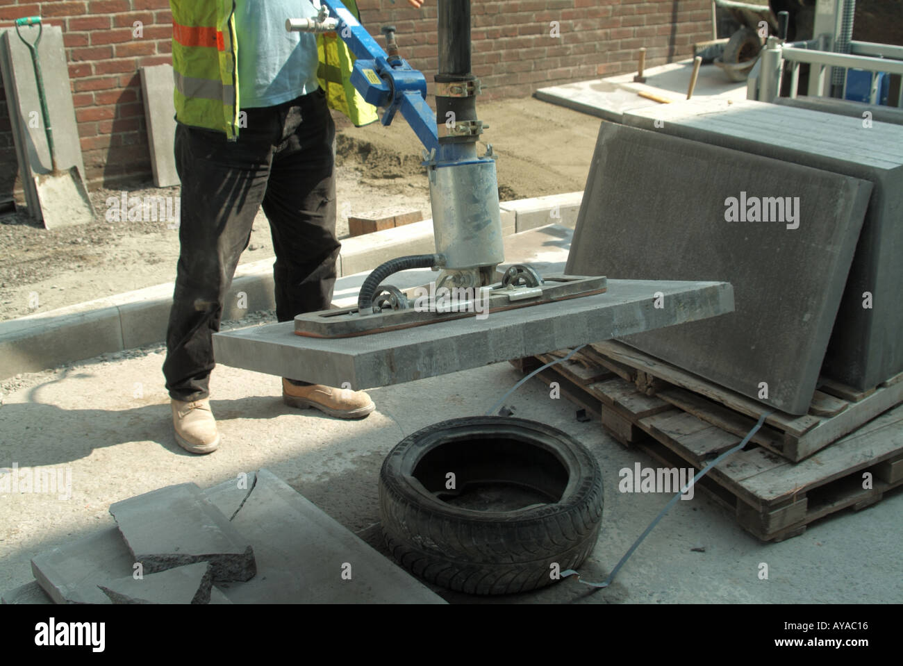 Close up of workman using a powered suction device to lift heavy street ...