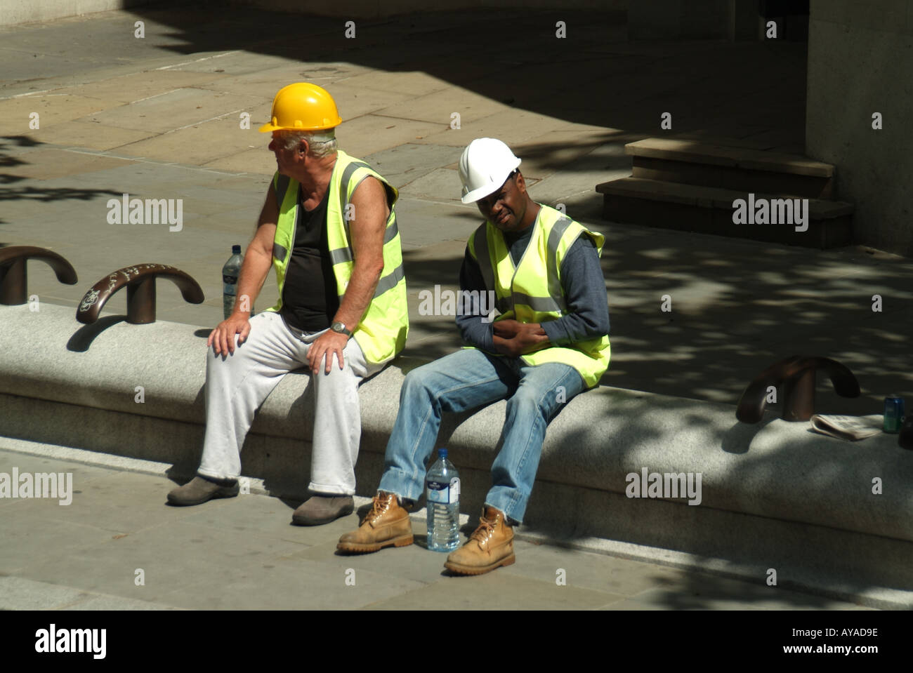 London two 2 building workers wearing safety clothing taking a break ...