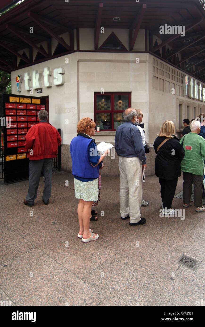 Queue of people waiting to purchase theatre tickets from booking kiosk ...