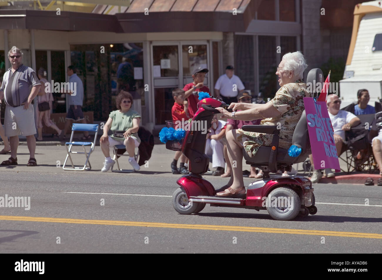 older woman riding electric wheeled chair scooter in parade Stock Photo ...