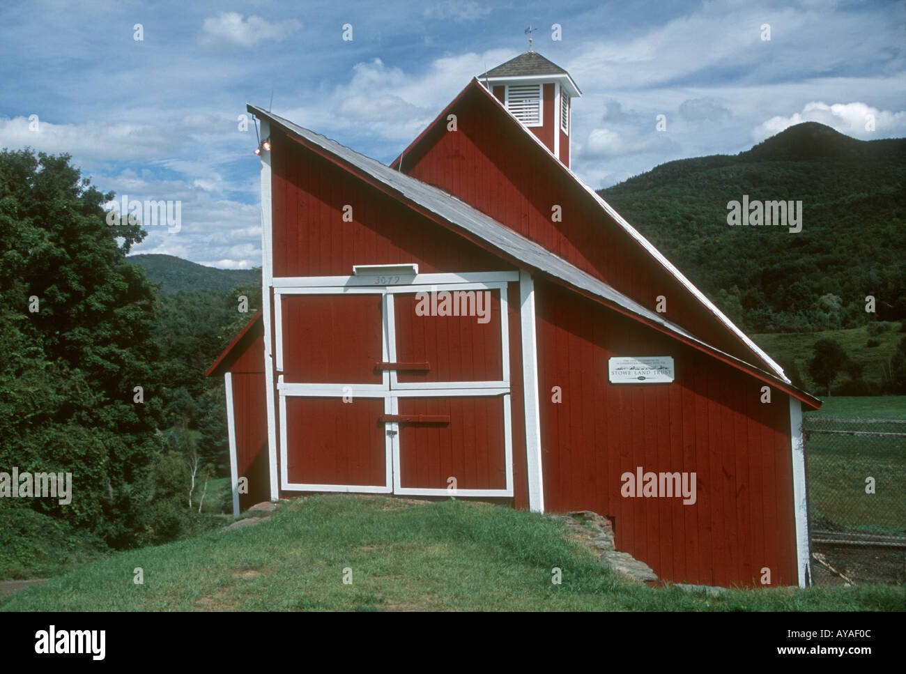 Red barn with white trim against blue sky with clouds Stowe Vermont ...