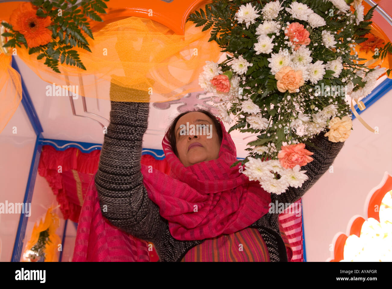 Sikh woman putting finishes touches to flowers on float for festival of ...