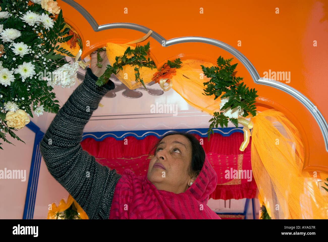 Sikh woman putting finishes touches to flowers on float for festival of ...