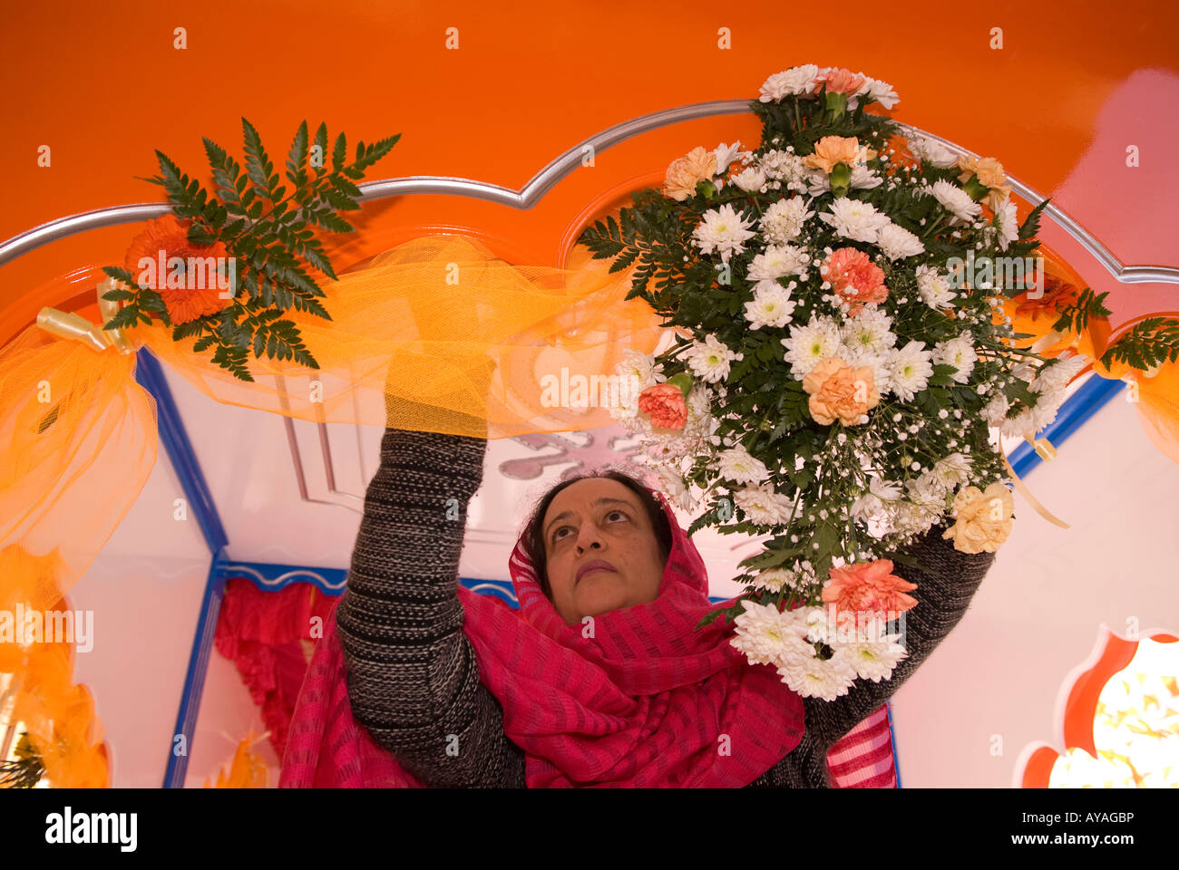 Sikh woman putting finishes touches to flowers on float for festival of ...