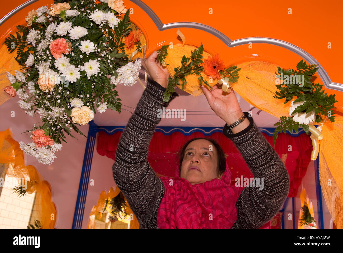 Sikh woman putting finishes touches to flowers on float for festival of ...