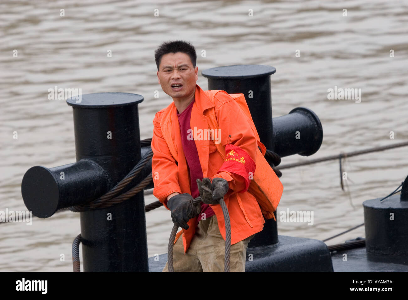 Ship worker pulling a cable on a barge on the Yangtze river in China ...