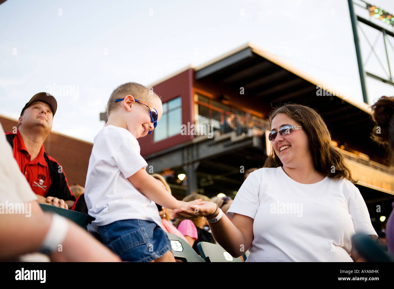Little boy at a baseball game with his parents Stock Photo - Alamy