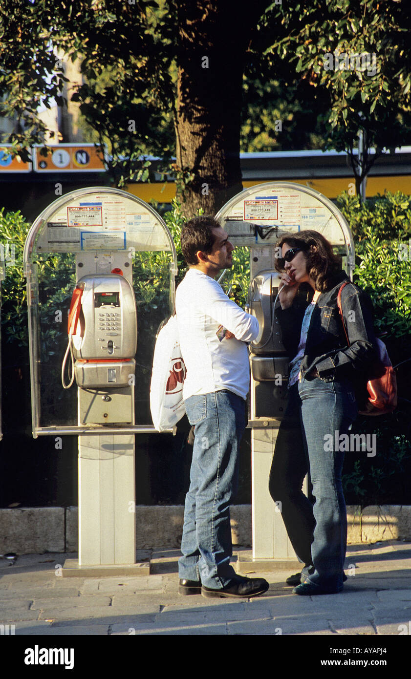 Two people using the public telephones in a street in Venice close up ...