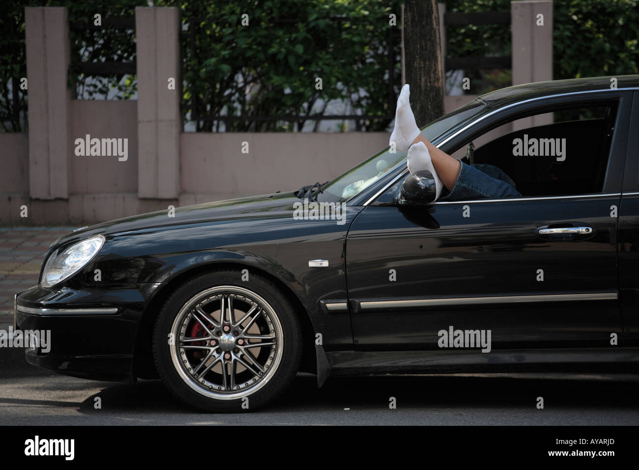 South Korea Seoul Driver rests with stocking feet out window of ...