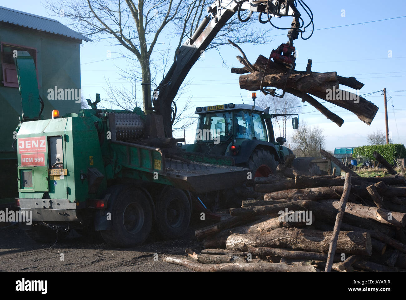 Chipping machine chipper loading logs with a grab Stock Photo - Alamy