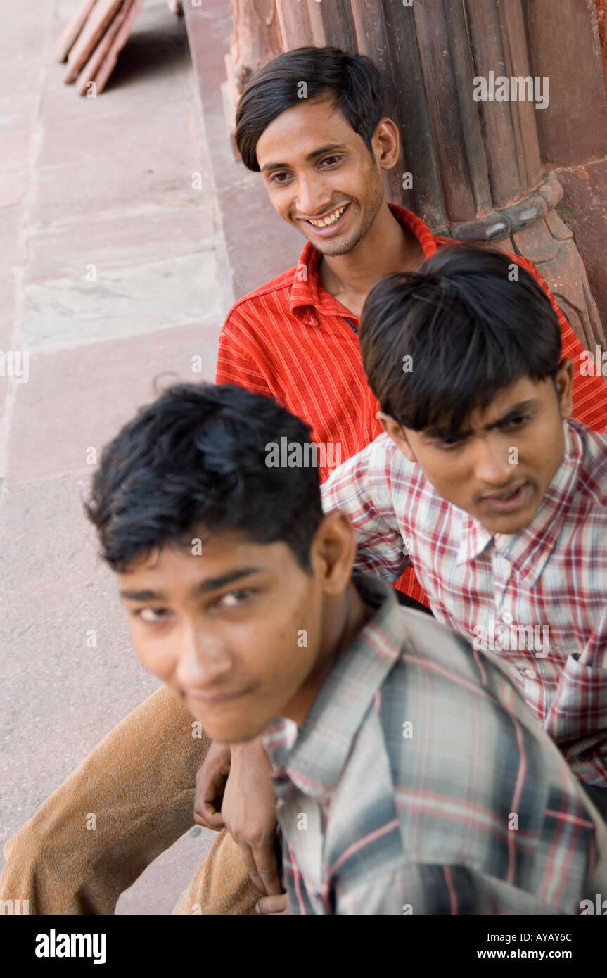 Three young Muslim men sat on the edge of courtyard of the Jama Masjid ...
