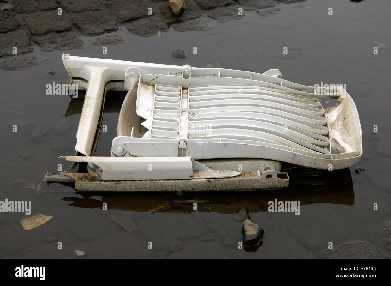 damaged plastic chair seat white puddle cobbles rubbish refuse garbage ...