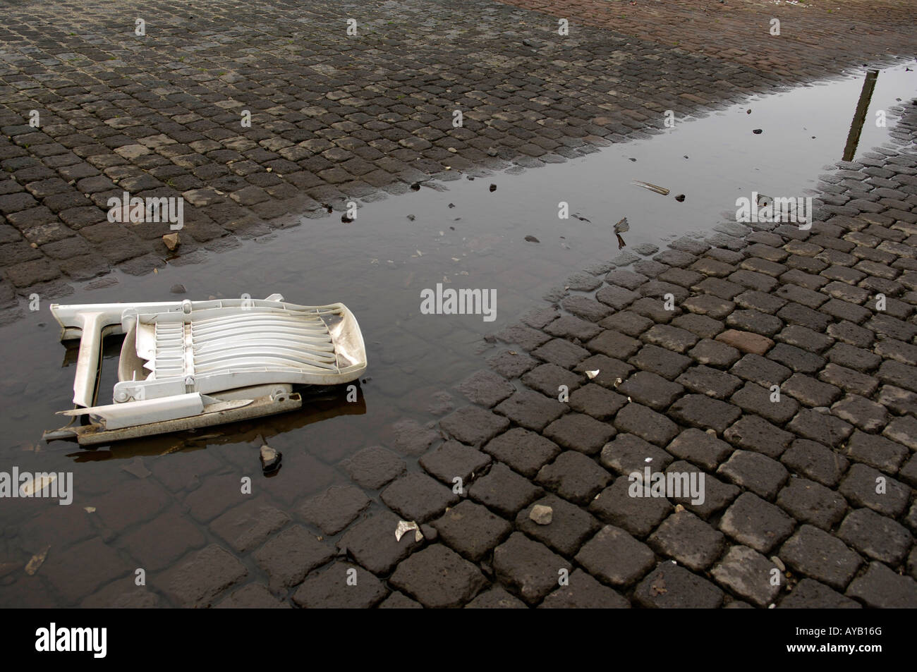 damaged plastic chair seat white puddle cobbles rubbish refuse garbage ...