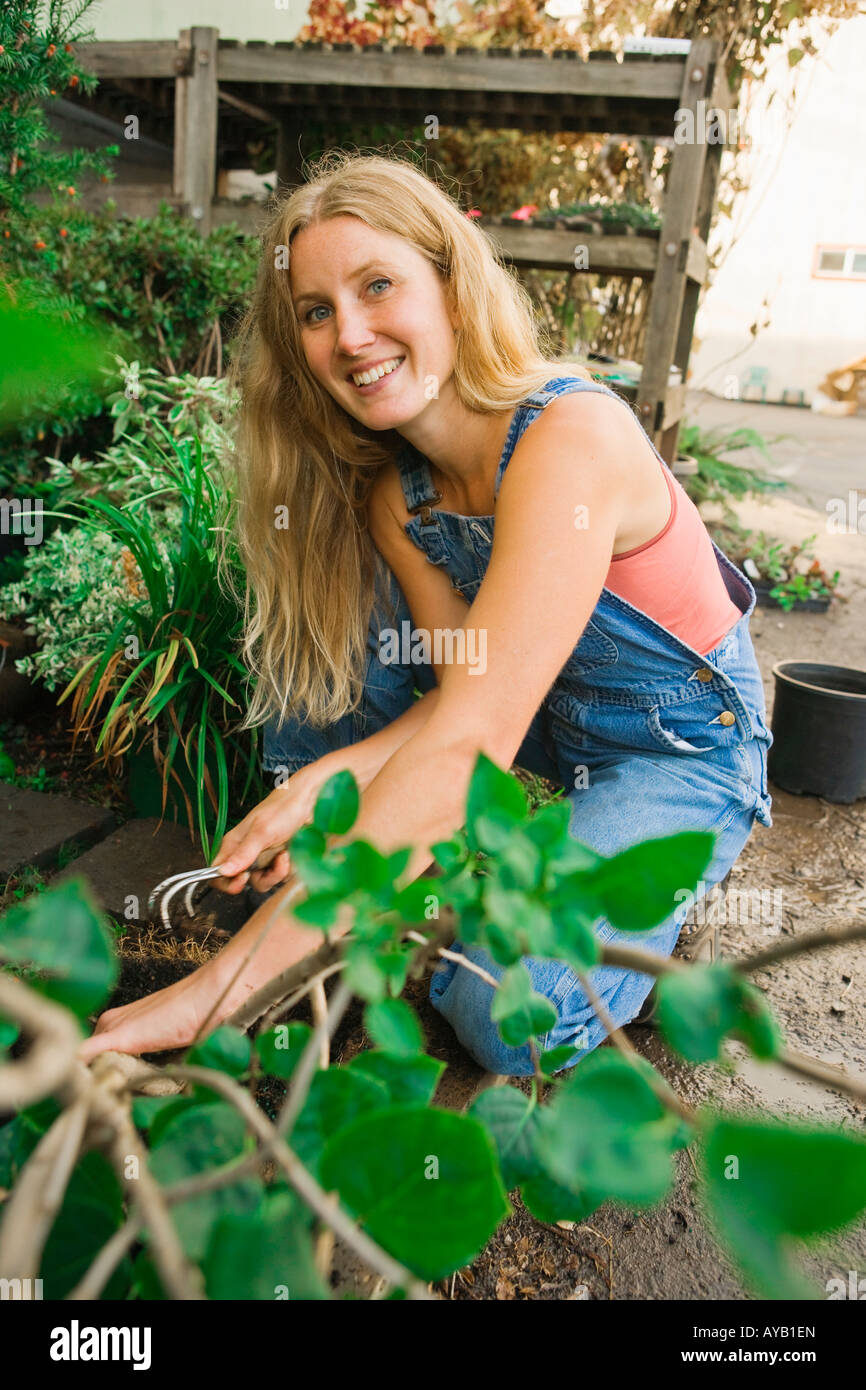 Portrait of a young woman working on a young tree in a plant nursery ...