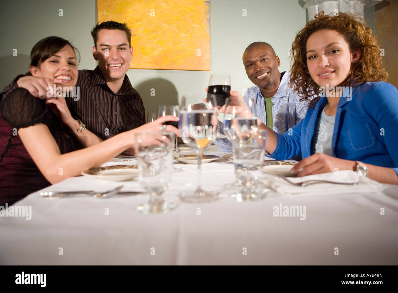 Portrait of two smiling young couples sitting at a restaurant table ...