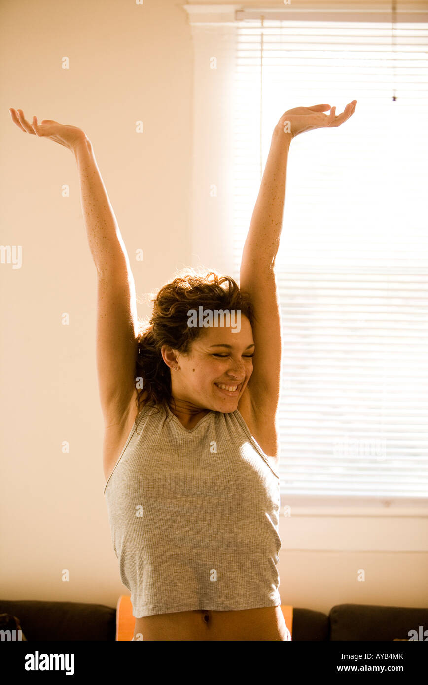 Smiling young woman stretching with arms up in the air Stock Photo - Alamy