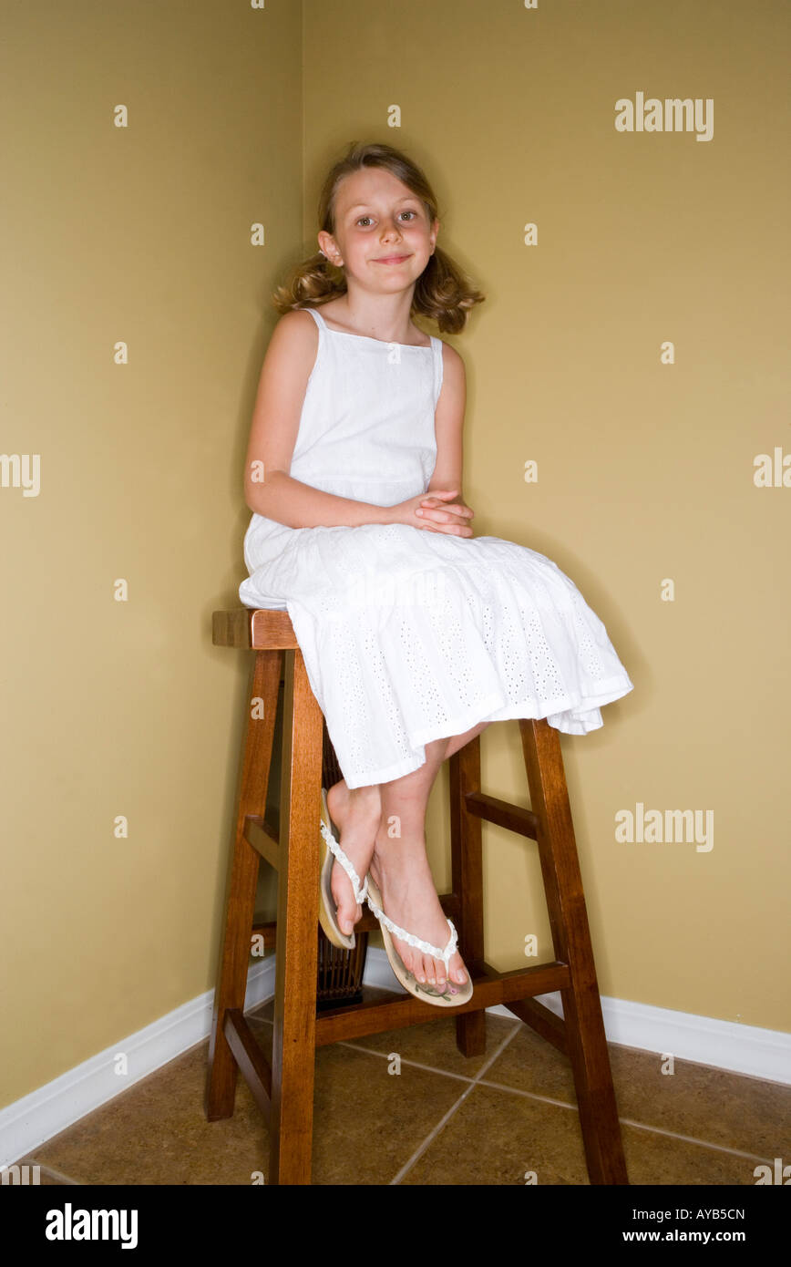 Girl sitting in corner on stool Stock Photo - Alamy