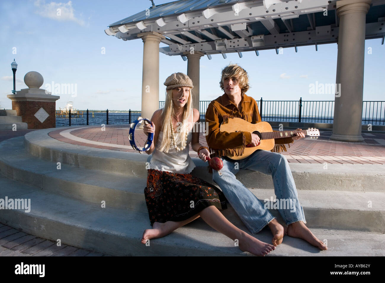 A young Hippie couple in a park playing guitar and tambourine Stock ...
