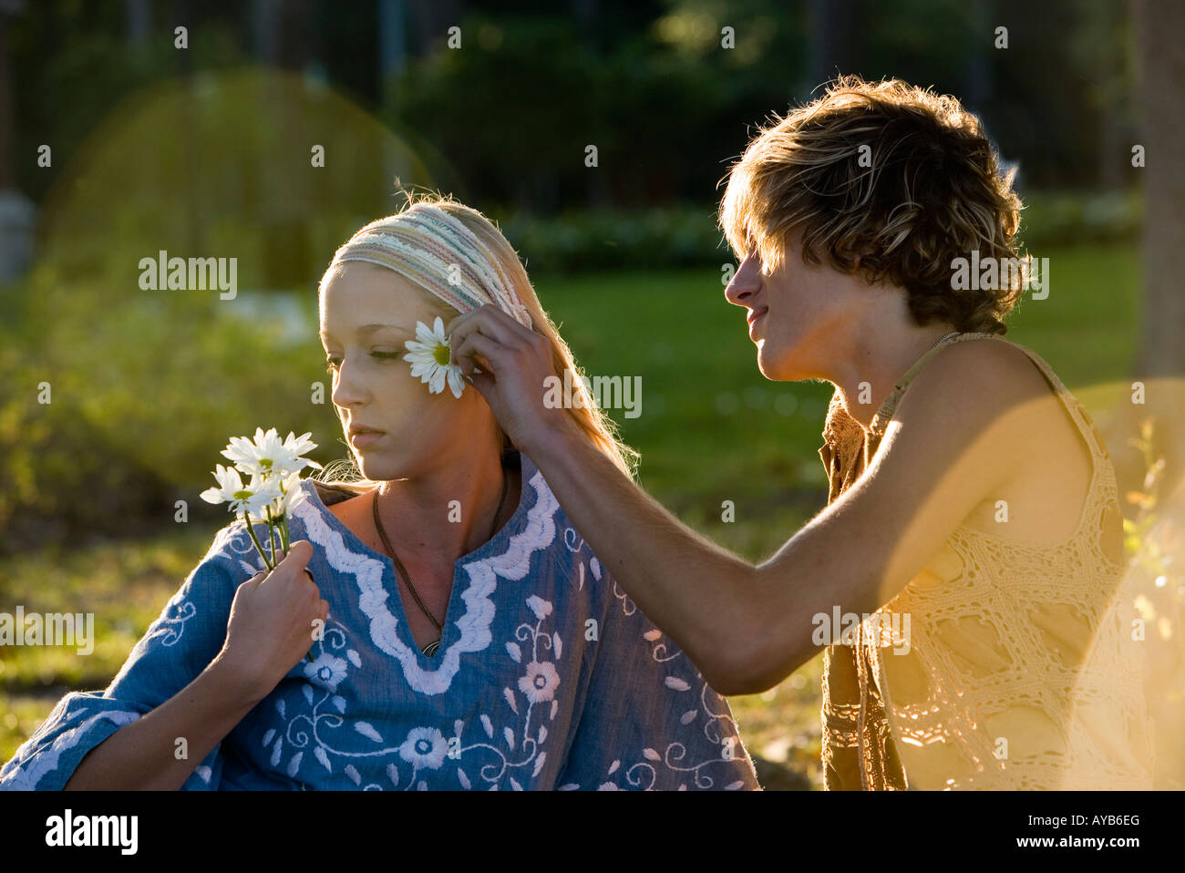 View of a young couple in vintage 1960's hippie, putting flower behind ...