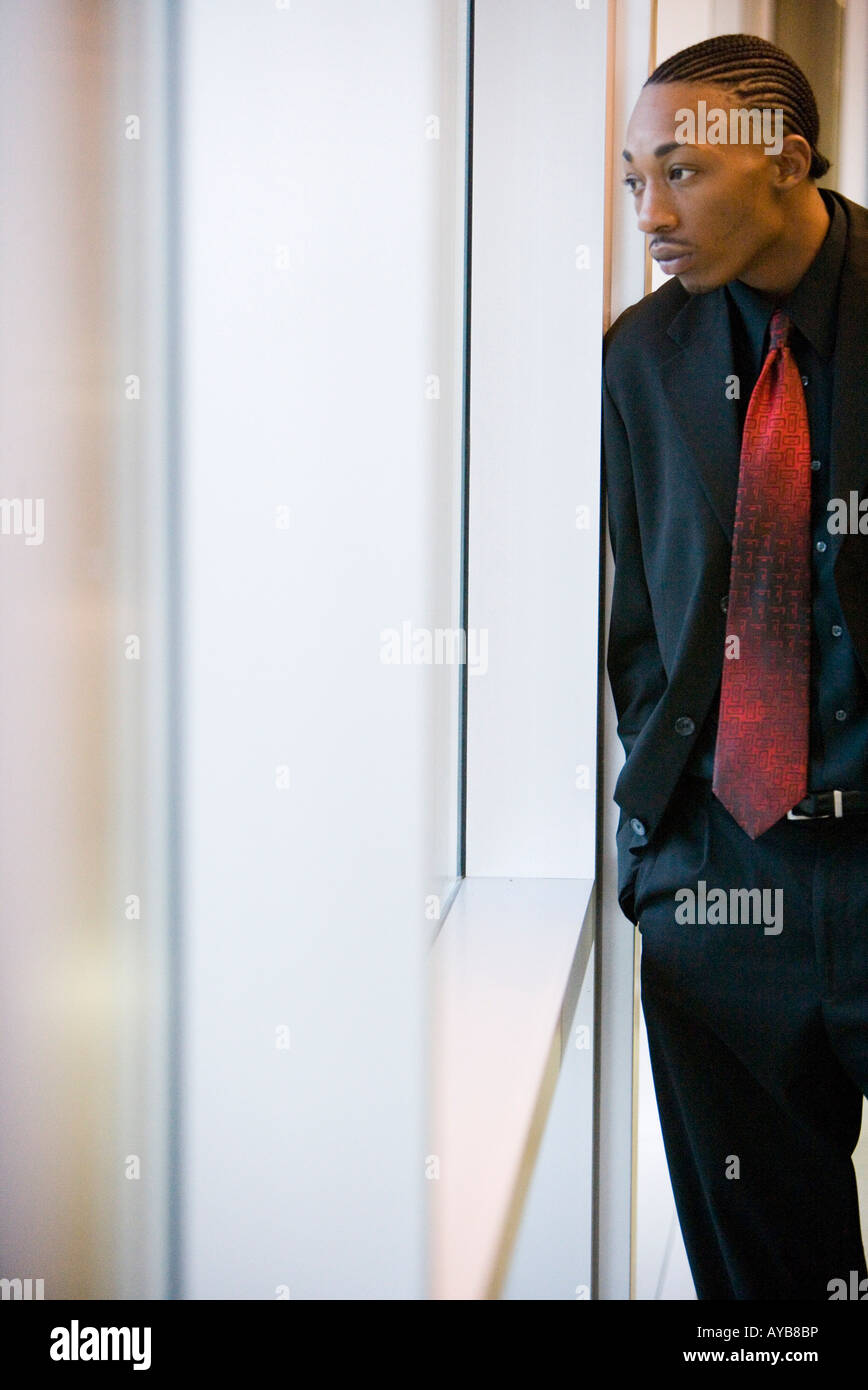Businessman standing and leaning against a window Stock Photo - Alamy
