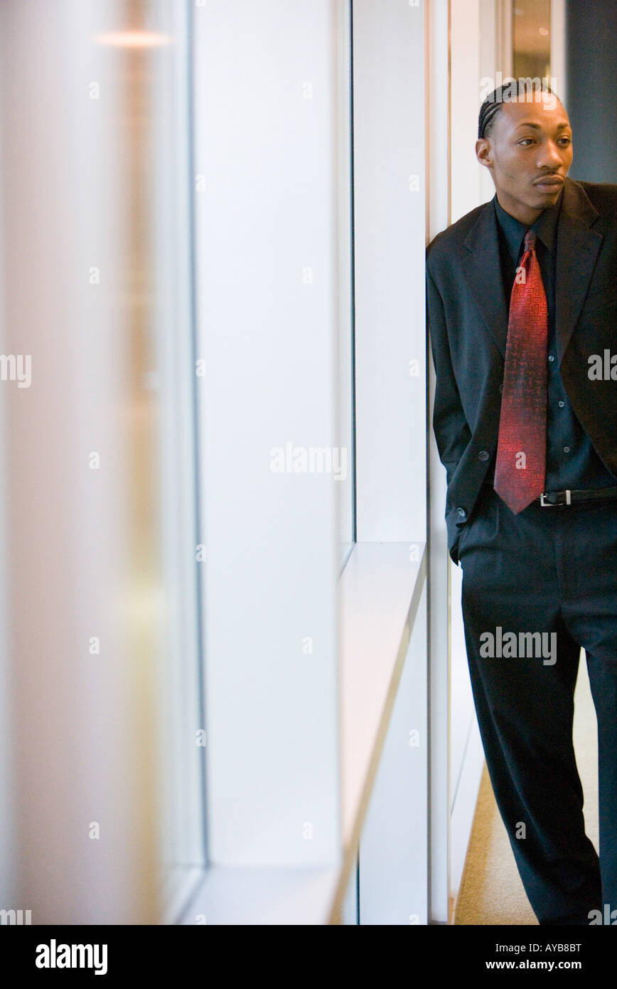 Businessman standing and leaning against a window Stock Photo - Alamy
